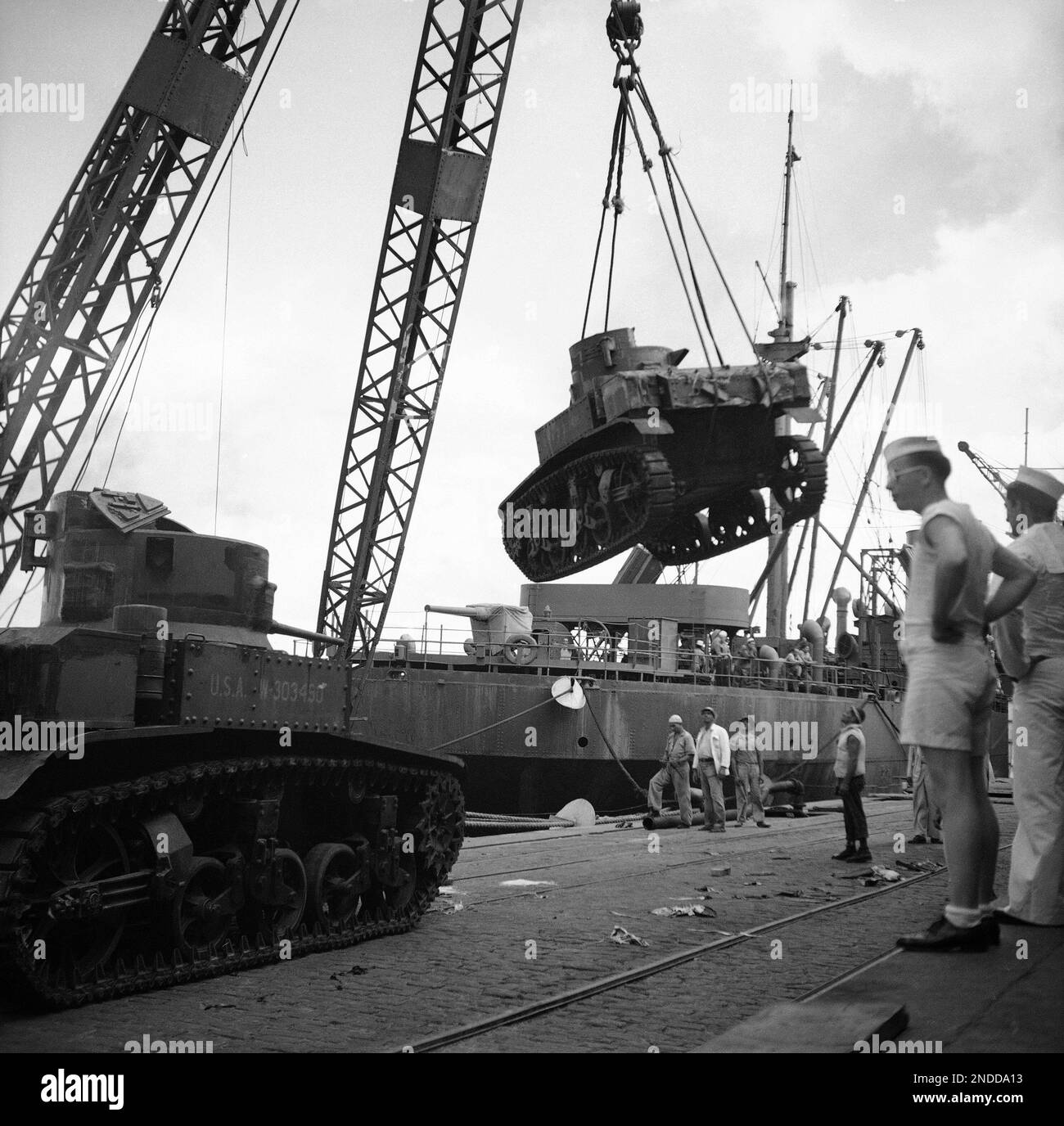U.S. sailors watch as light tanks from the United States are swung from ...
