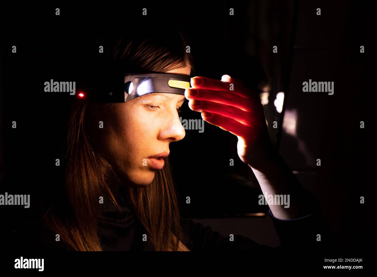 A girl with a headlamp shines in the dark, the light of a lantern Stock ...