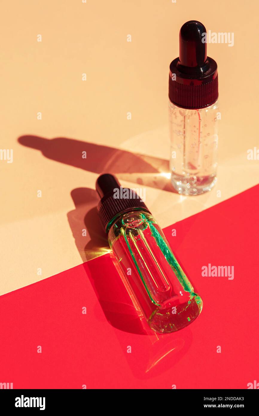 Two glass bottles with cosmetic liquid on bright red background with ...