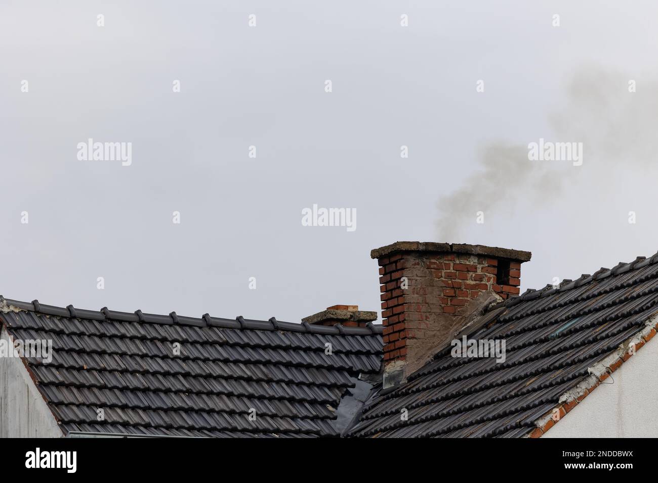 Toxic smoke flying from the chimney of a detached house. Combating smog ...
