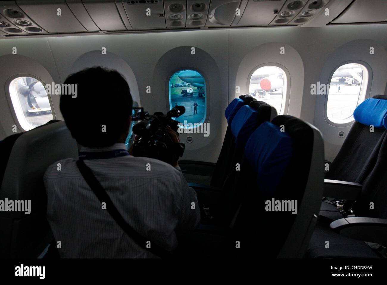 A camera man films a shutterless window, center, of a Boeing 787 ...