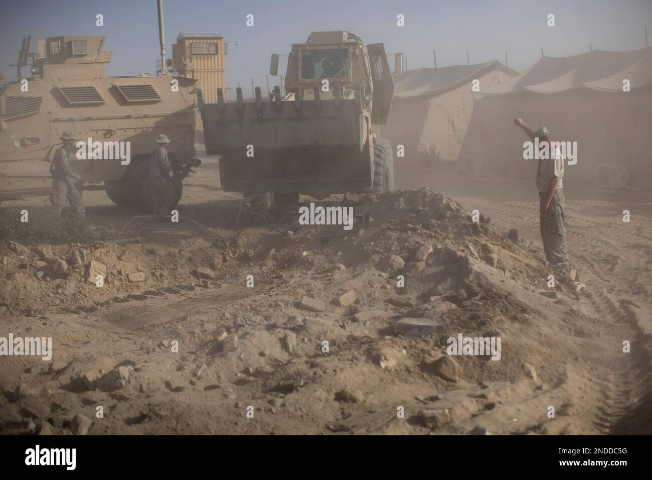 A U.S. Army soldier guides an earthmover operator at Combat Outpost ...