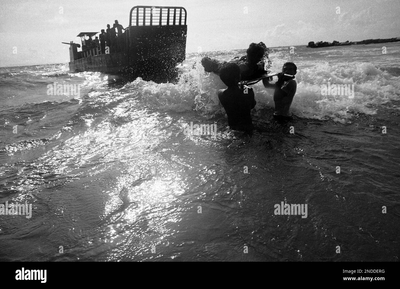 Cambodian soldiers carry a wounded comrade through pounding surf to a ...