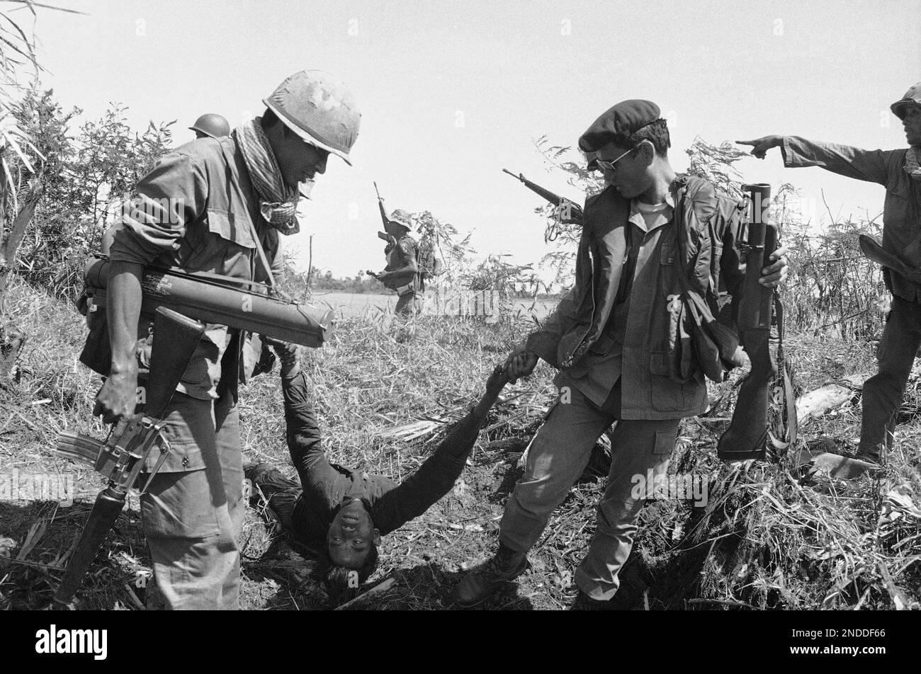 Two Cambodian soldiers drag a wounded Khmer Rouge Guerrilla from a ...