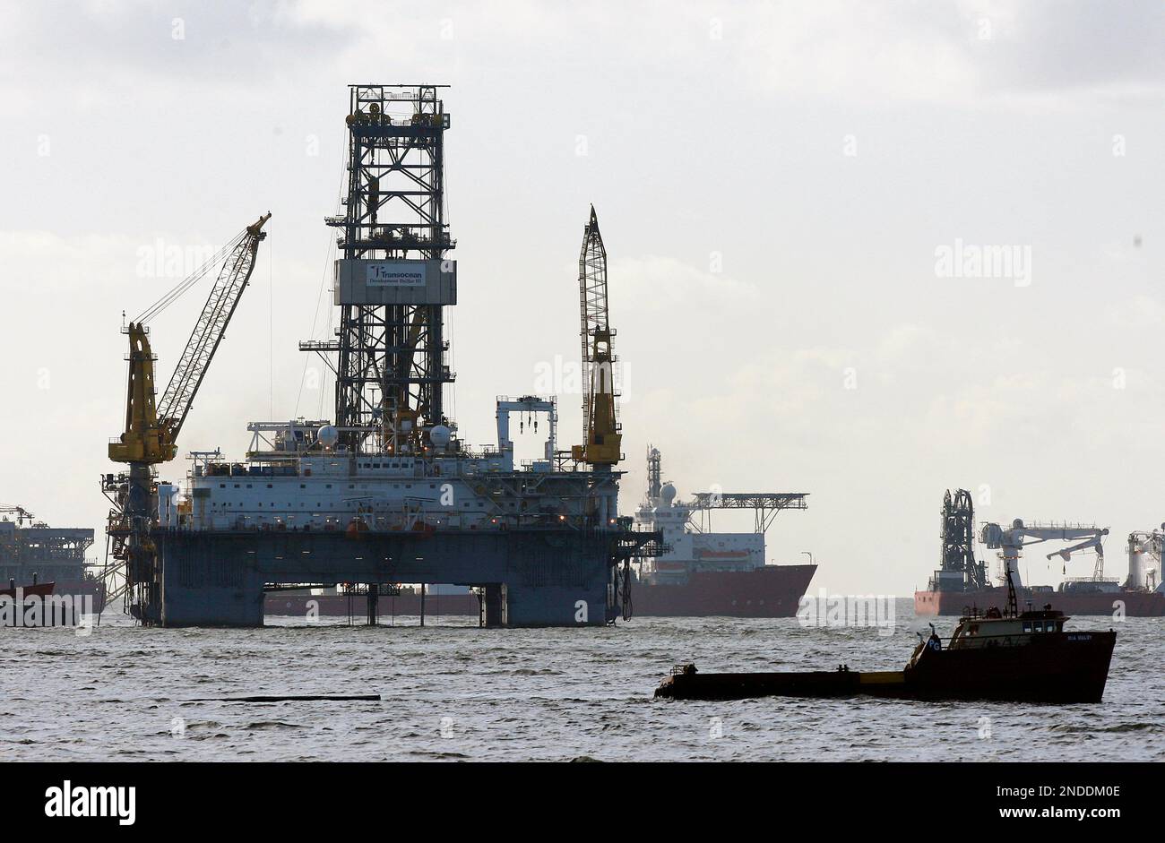 A ship pulling oil booms passes vessels assisting in the capping of the ...