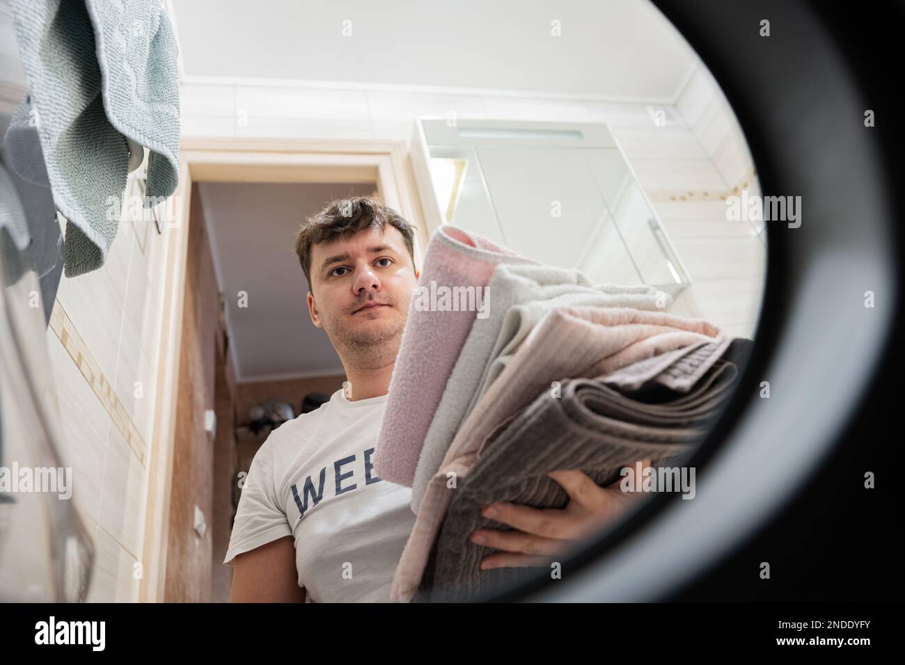 Man view from washing machine inside. Male does laundry daily routine ...