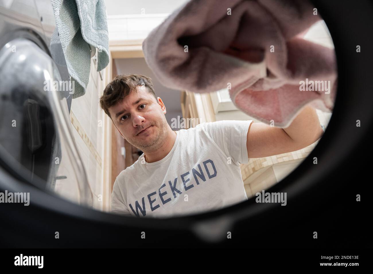 Man view from washing machine inside. Male does laundry daily routine ...