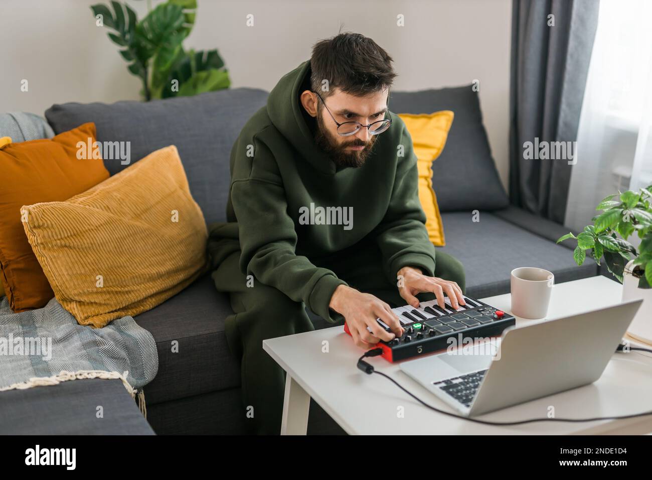 Man music producer or arranger using laptop and midi keyboard and other ...