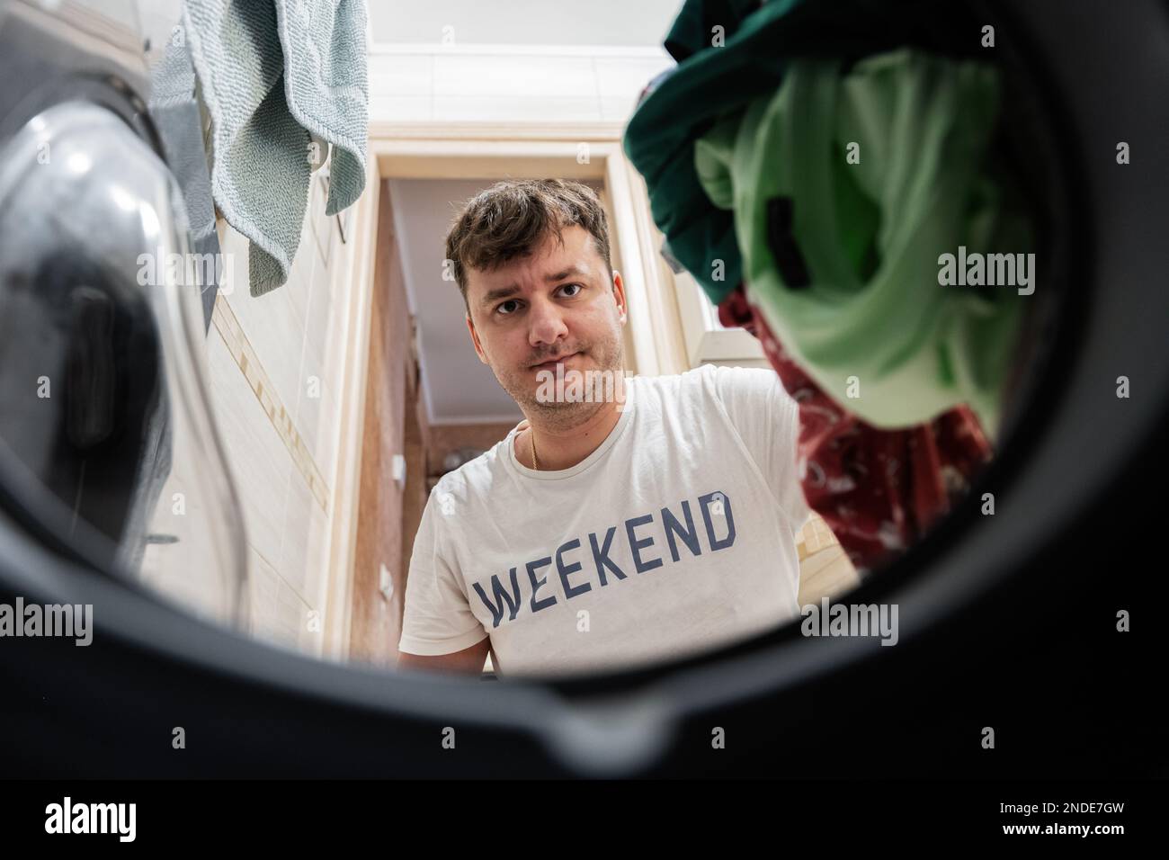 Man view from washing machine inside. Male does laundry daily routine ...