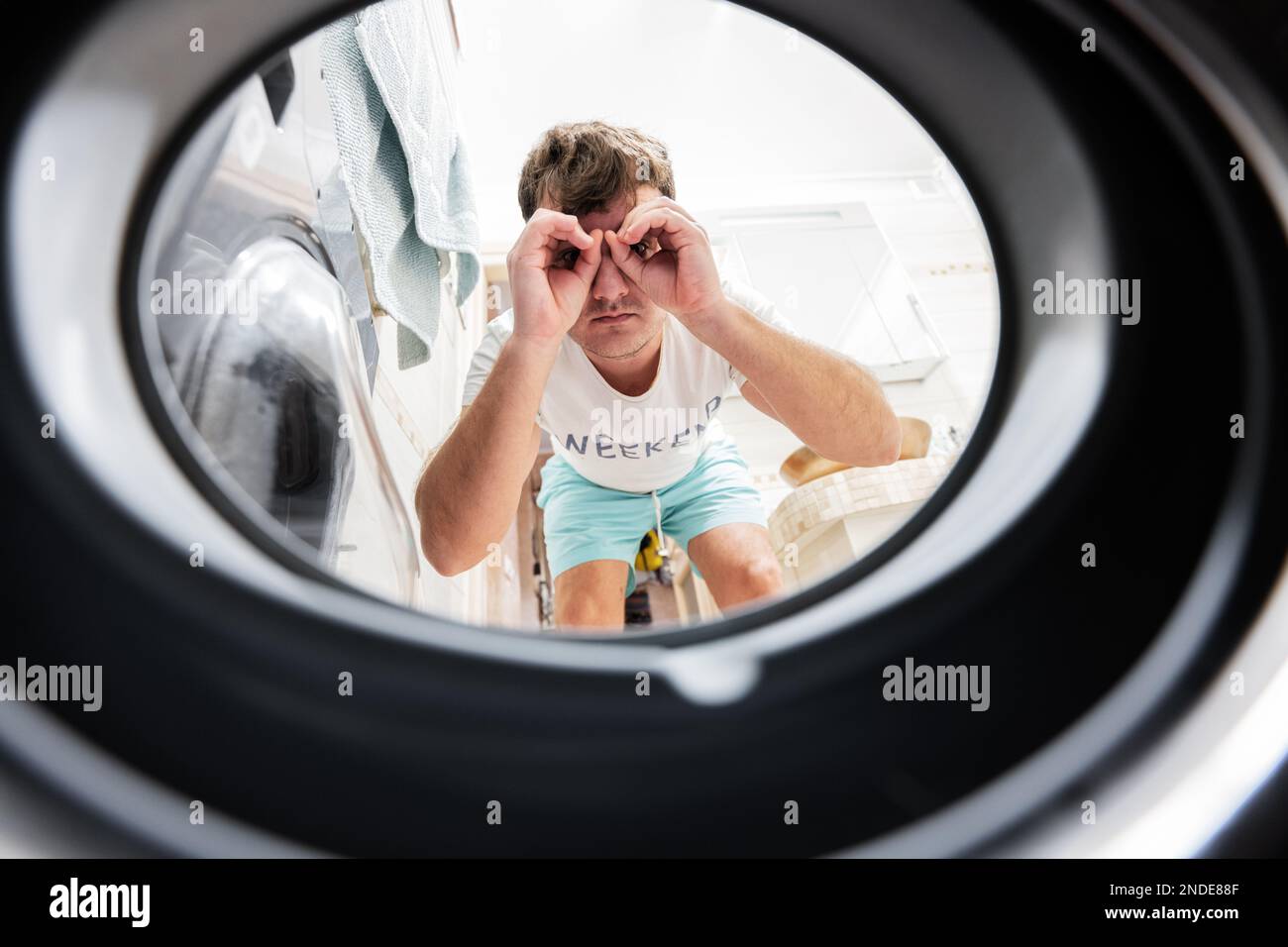 Man view from washing machine inside. Male does laundry daily routine ...