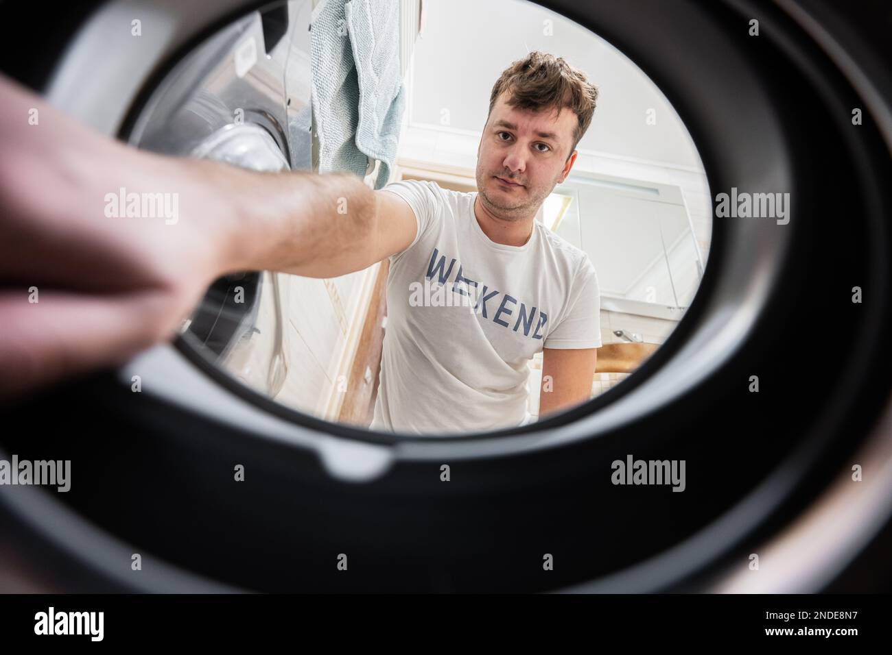 Man view from washing machine inside. Male does laundry daily routine ...