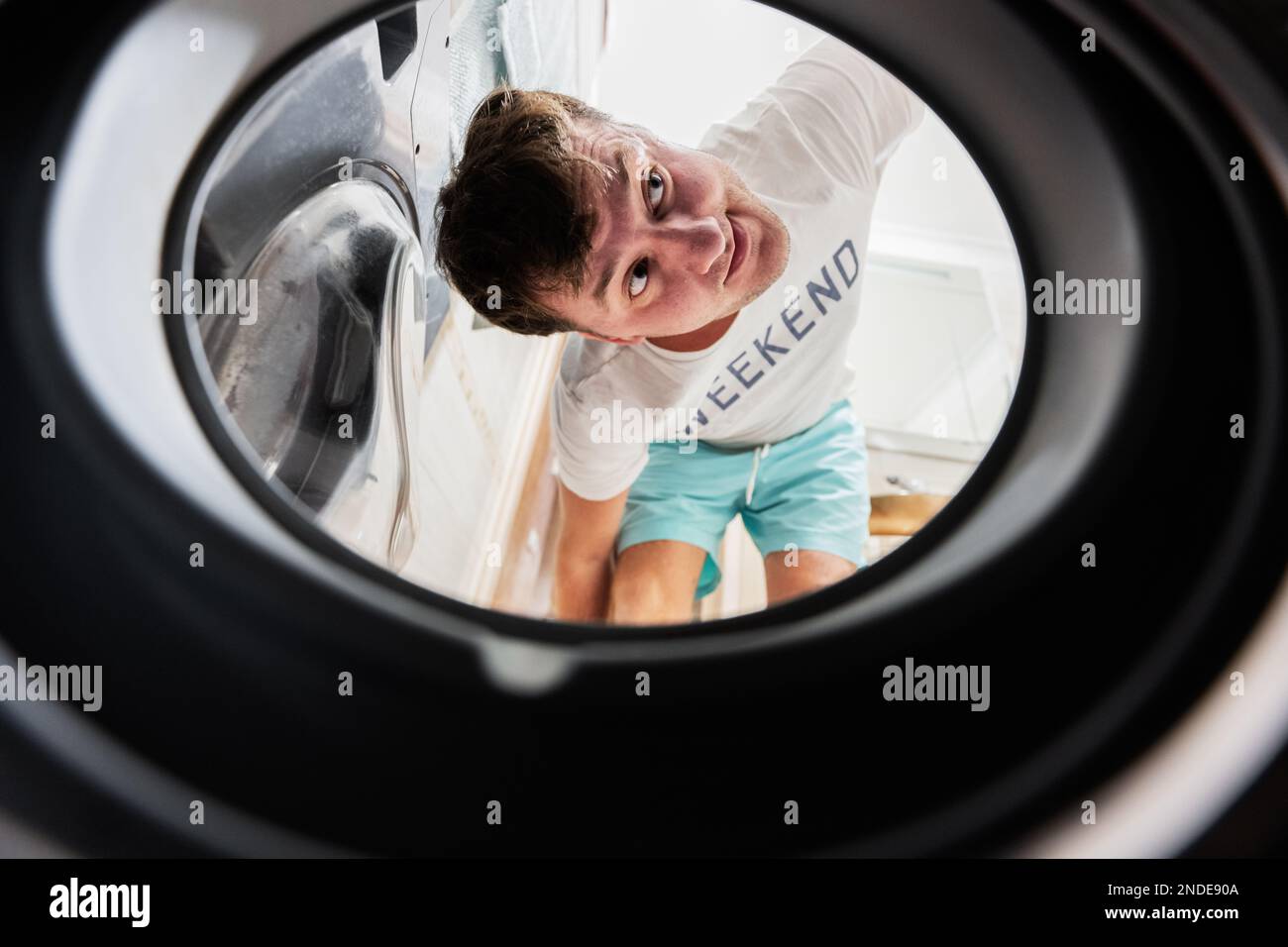 Man view from washing machine inside. Male does laundry daily routine ...