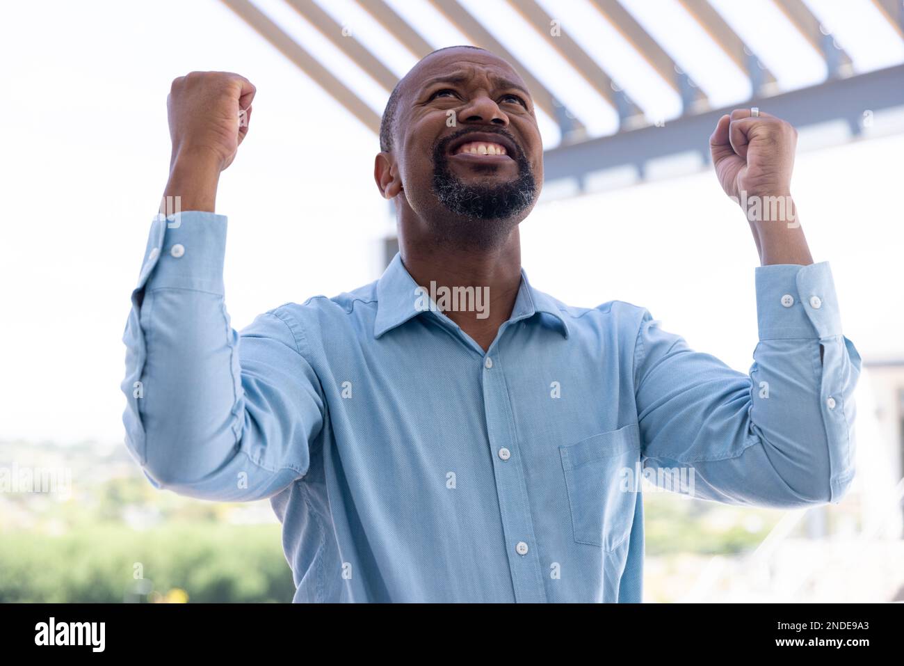 Happy african american businessman raising hands outside modern office ...