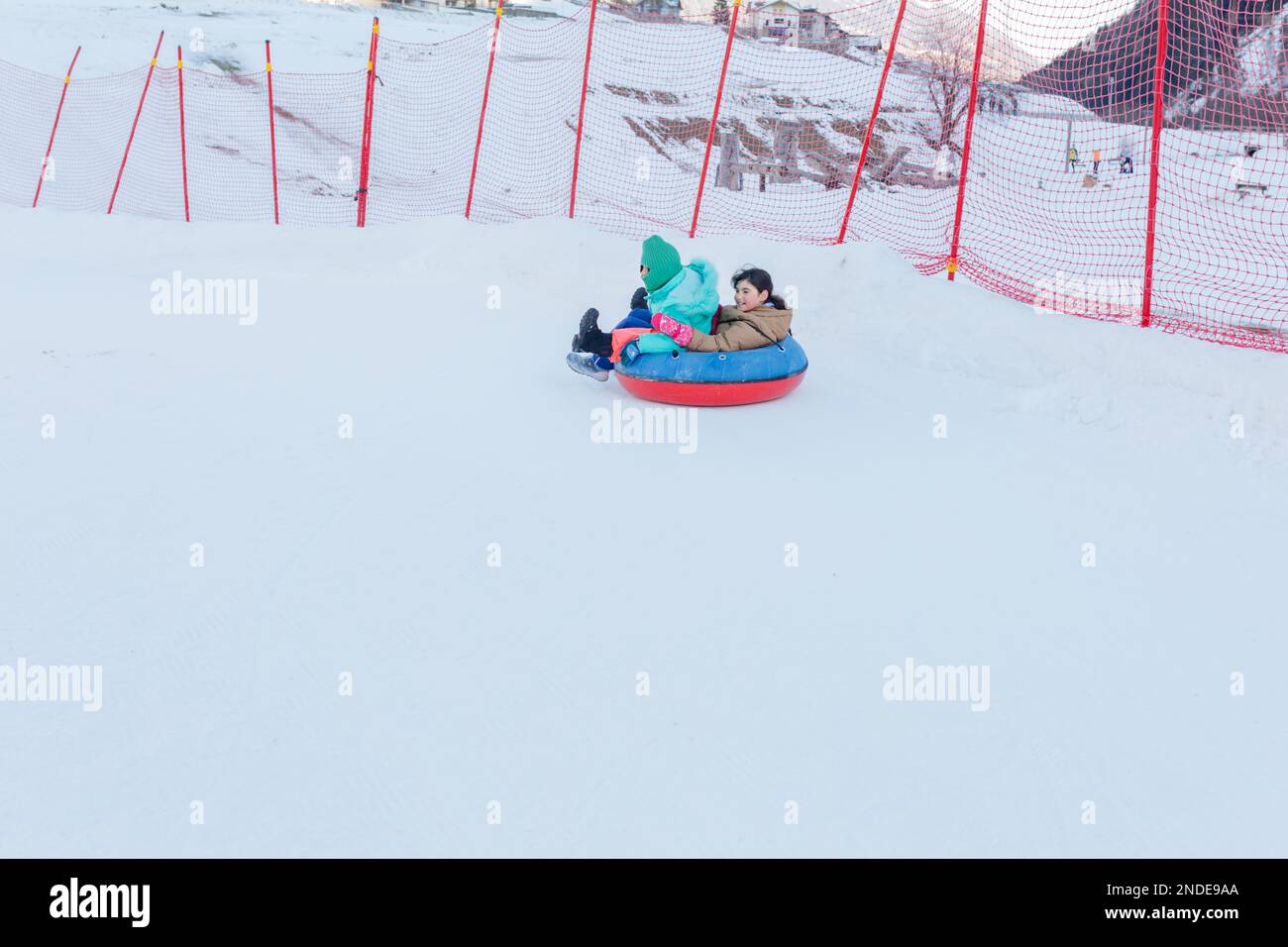 two children sledding on snow slope in one snow bob Stock Photo - Alamy