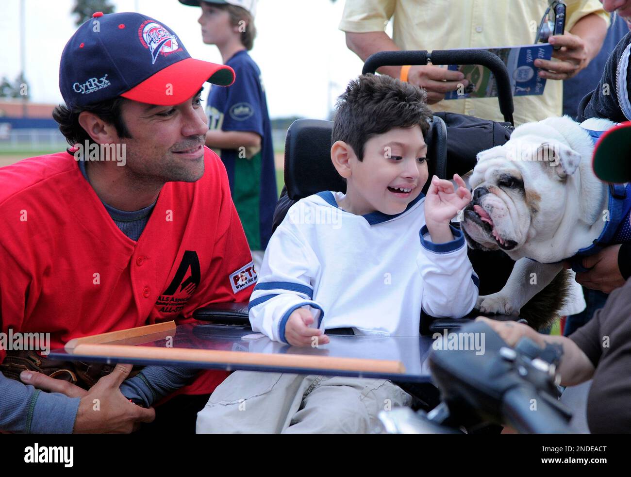 Dominic Bumo, center, who has ALS, pets a dog named Lyle as actor Danny ...