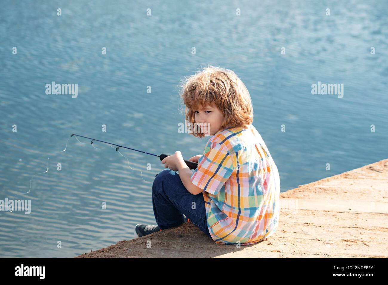 Kid boy fishing on the lake. Young fisher. Boy with spinner at river ...