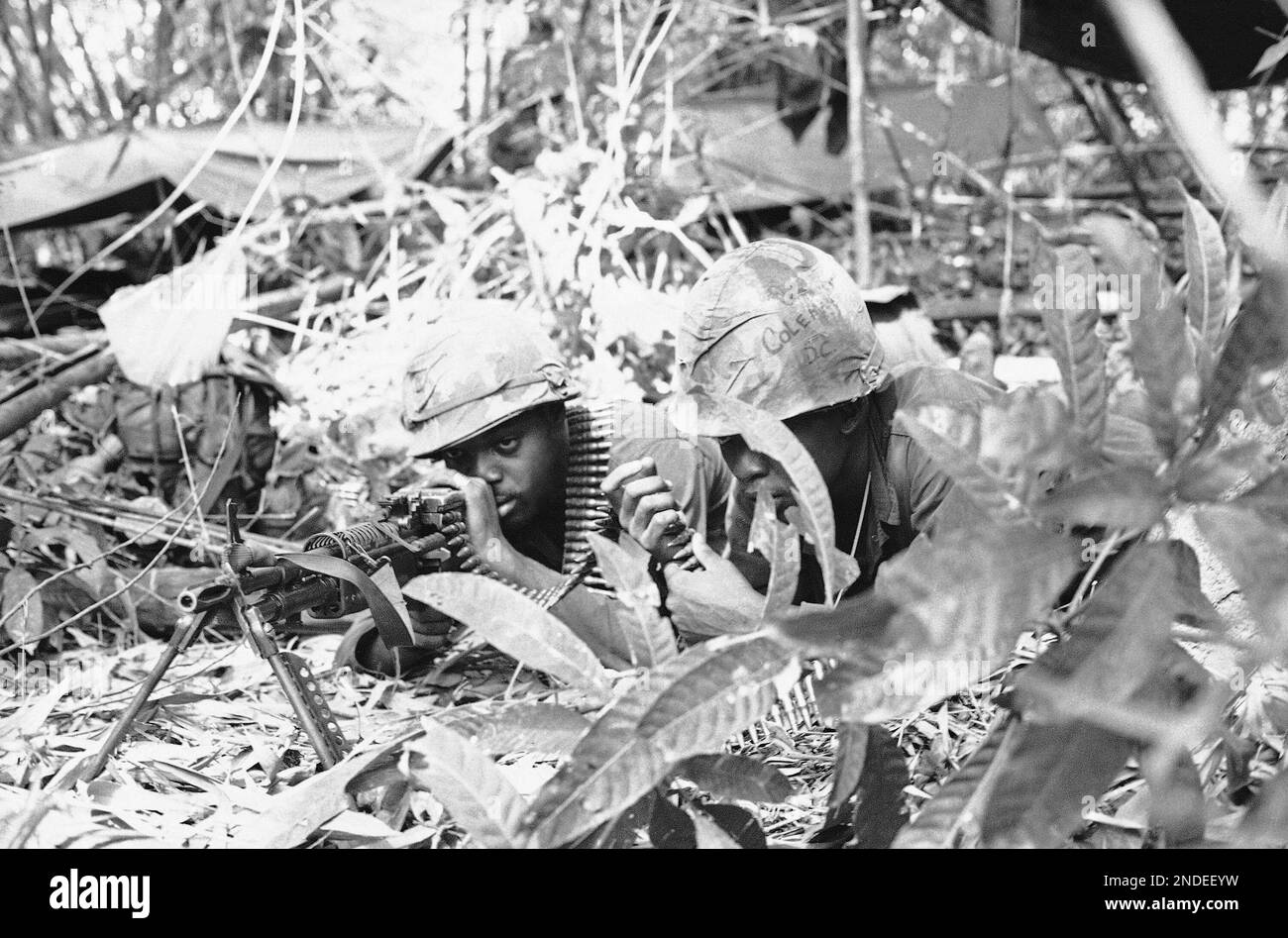 Two U.S. troopers fire their M-60 machine gun into thick undergrowth at ...
