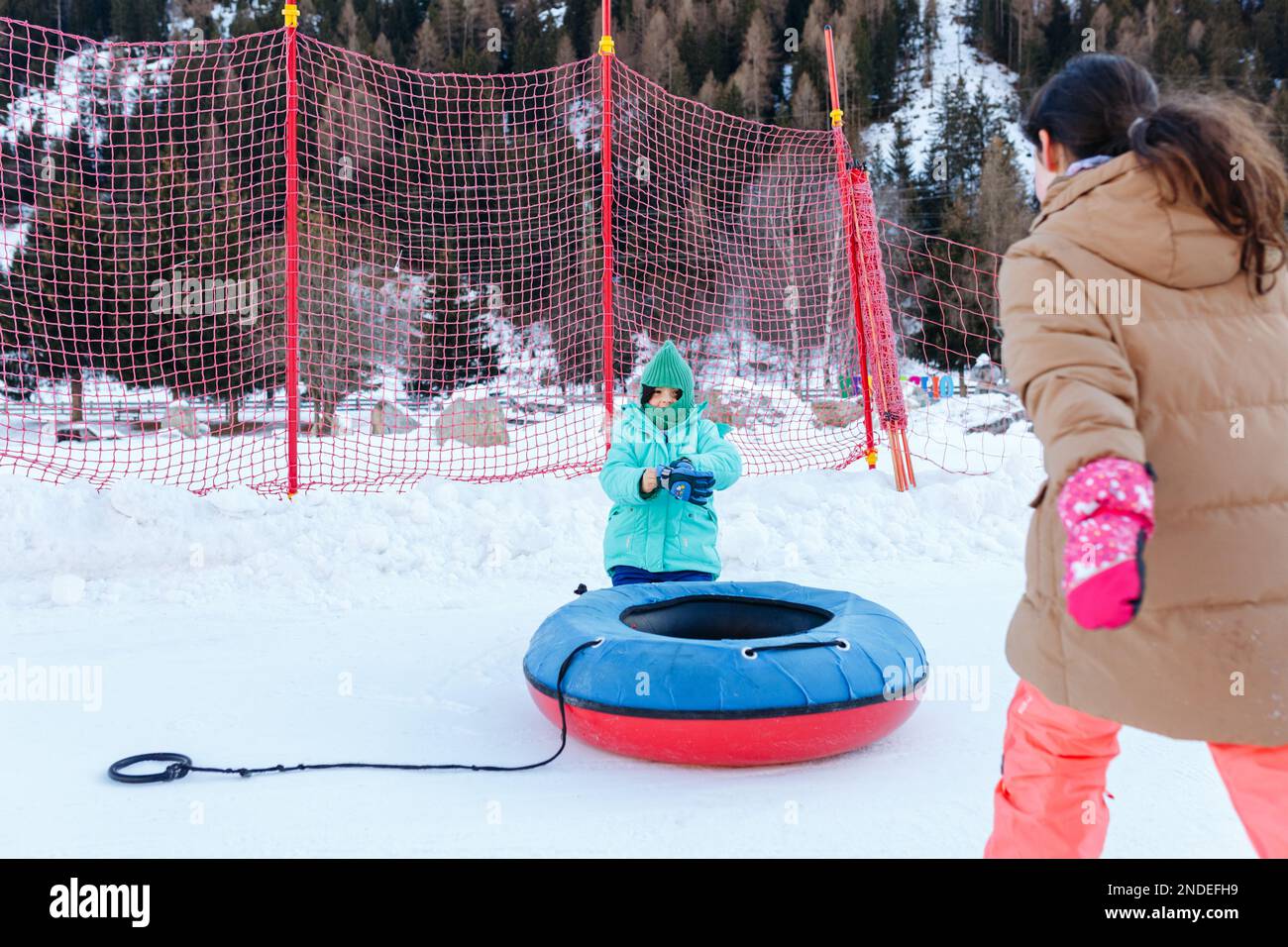 two children playing on snow slope with one snow bob Stock Photo - Alamy