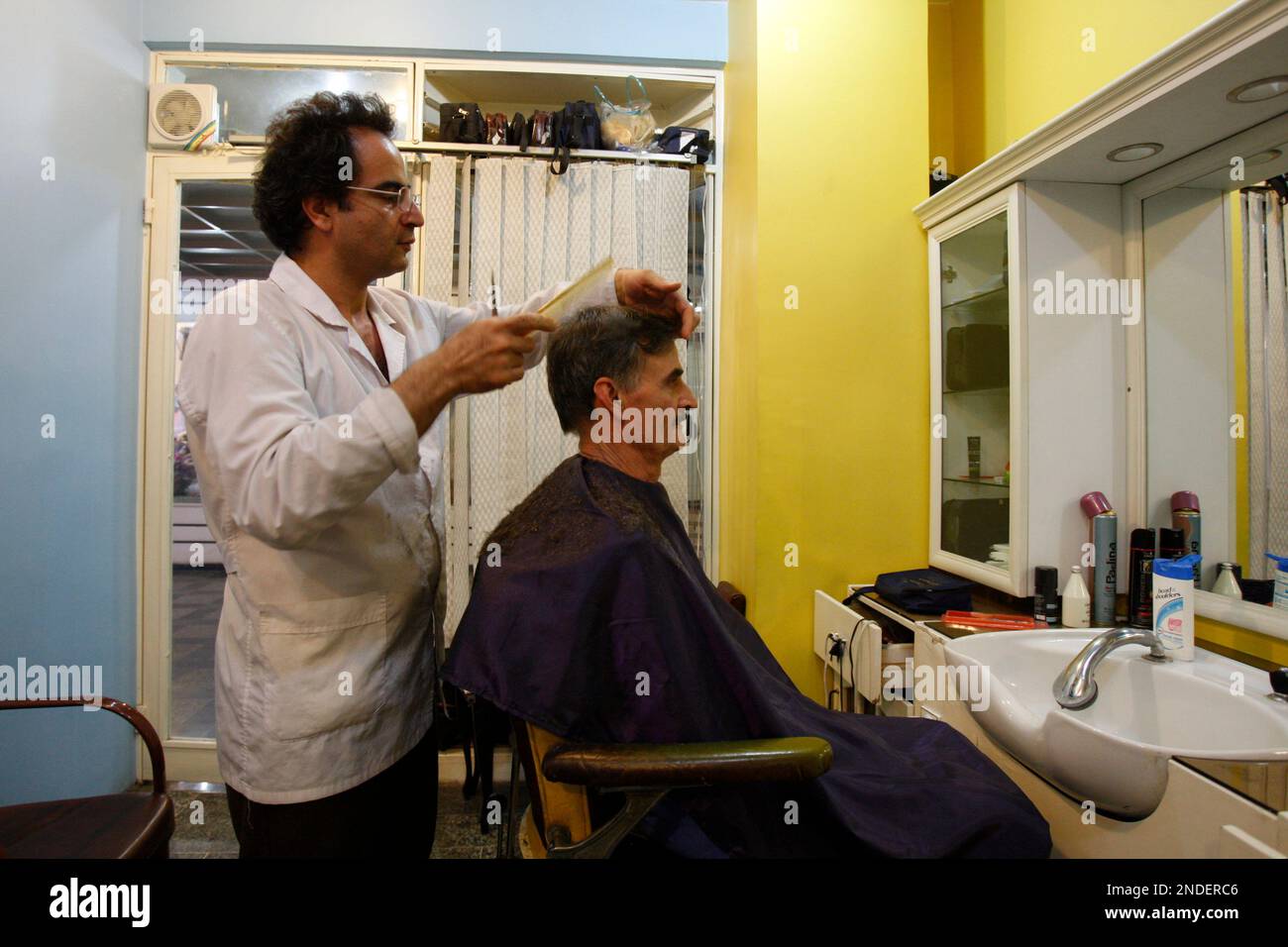 Barber Hassan Rezaei cuts hair in his barber shop in northern Tehran ...