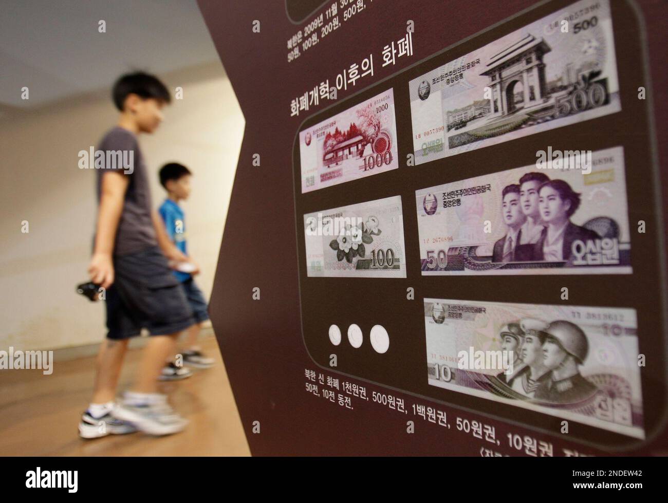 Children walk past the pictures of new North Korean banknotes on ...