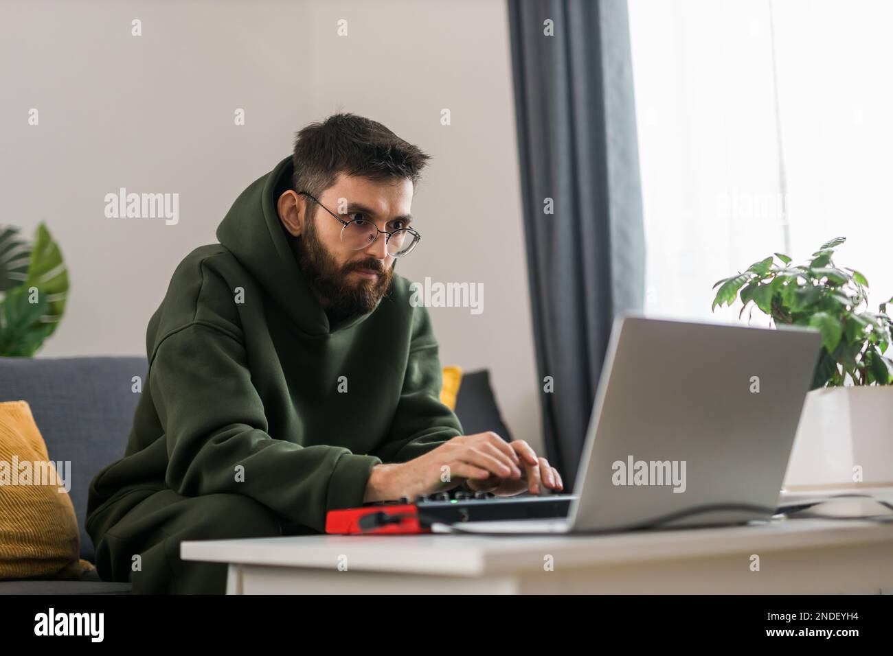 Man music producer or arranger using laptop and midi keyboard and other ...