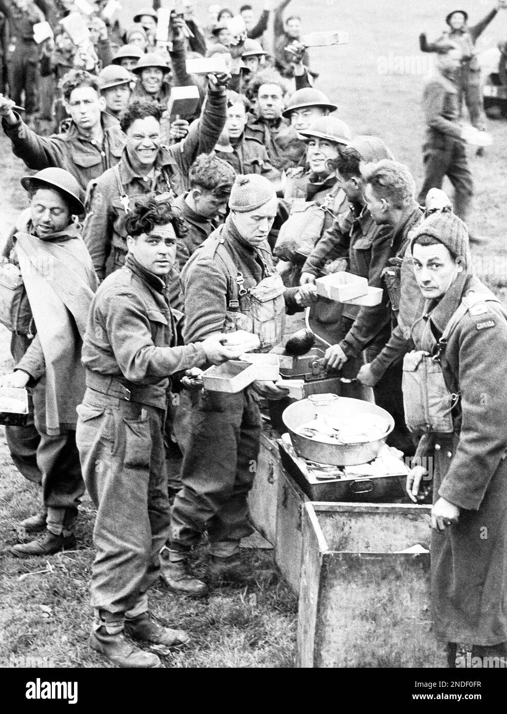 A group of Canadian troops get their lunch from an open air kitchen ...