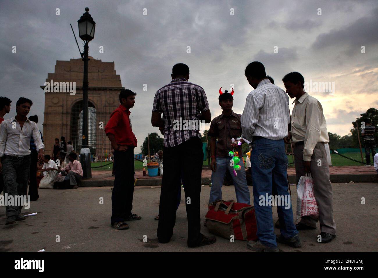 People crowd around the India Gate monument in the backdrop of monsoon ...