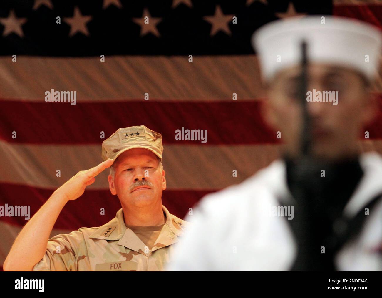 U.S. Navy Vice Adm. Mark Fox, left, salutes in front of the U.S. flag ...