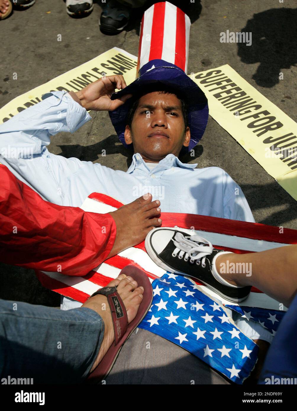 Activists step on their colleague who is dressed as Uncle Sam during a ...