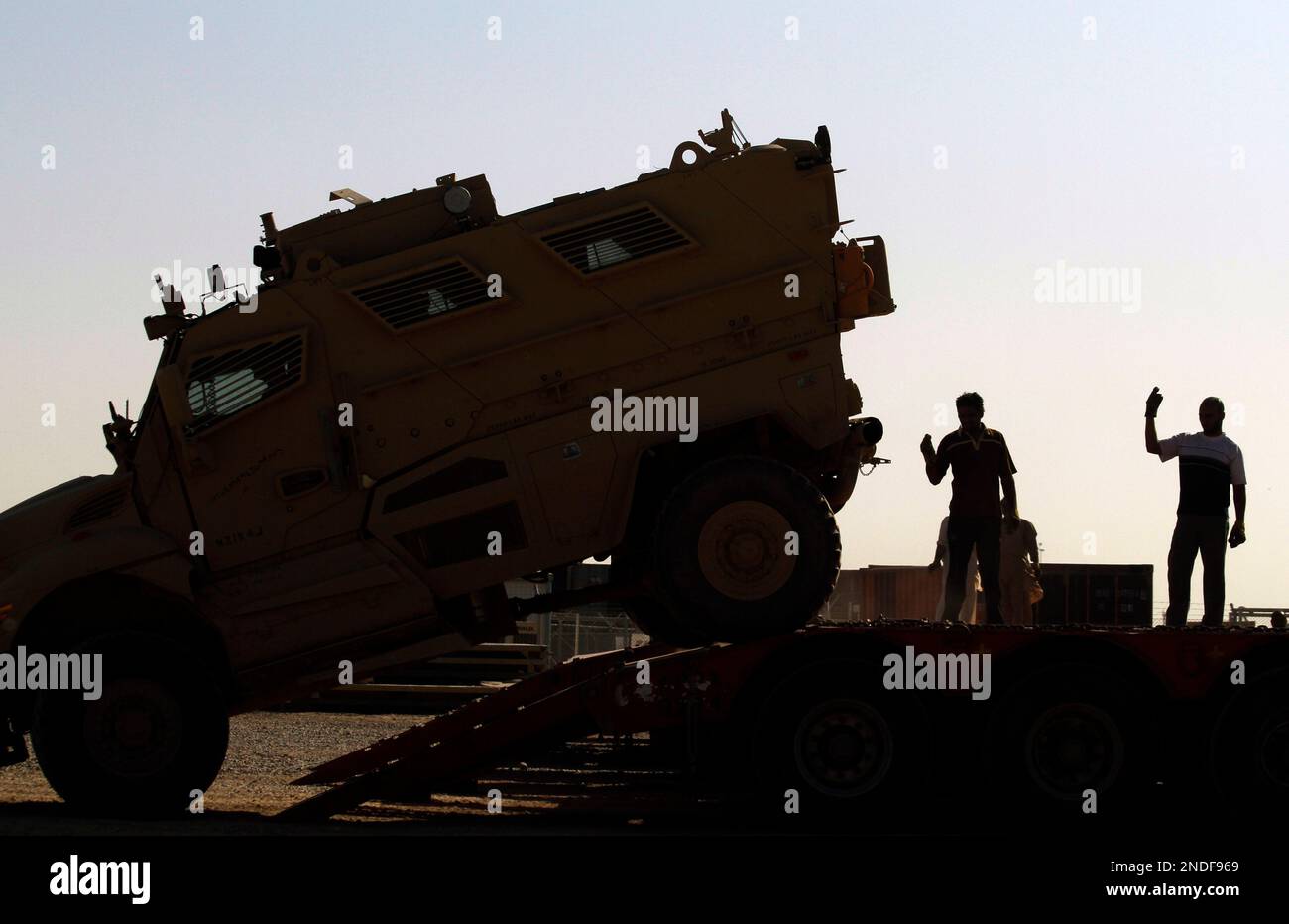 Iraqi truck drivers use hand signals to help guide a US military mine ...
