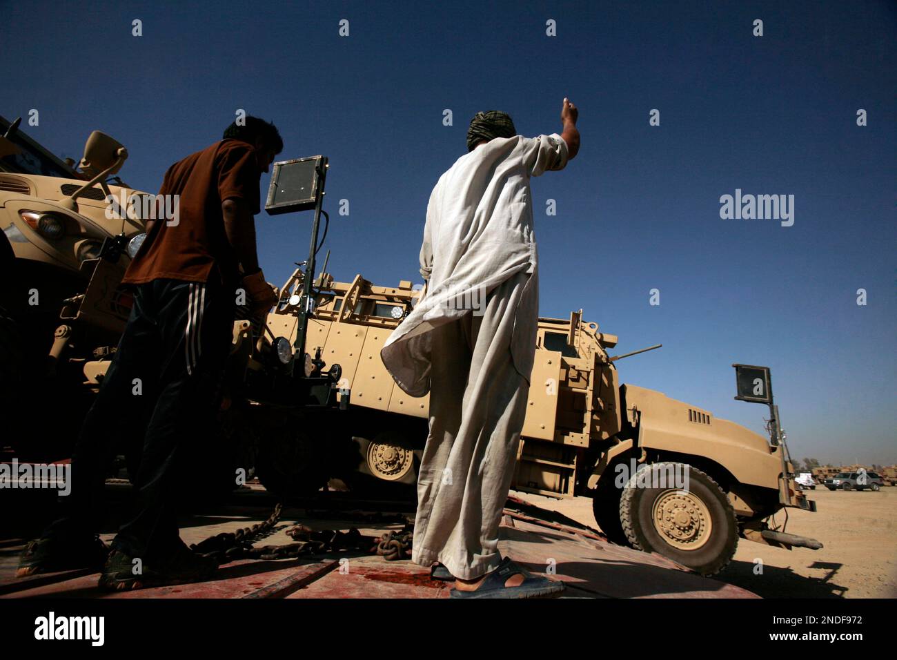 An Iraqi truck driver uses hand signals to help guide a US military ...