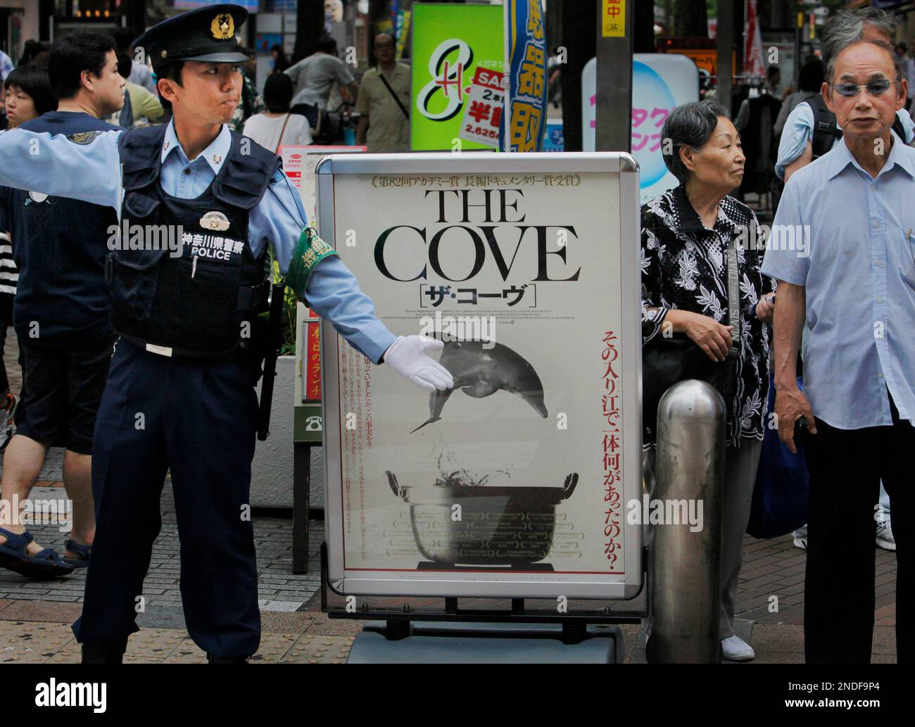 A Japanese police officer stands guard in front of a movie theater ...