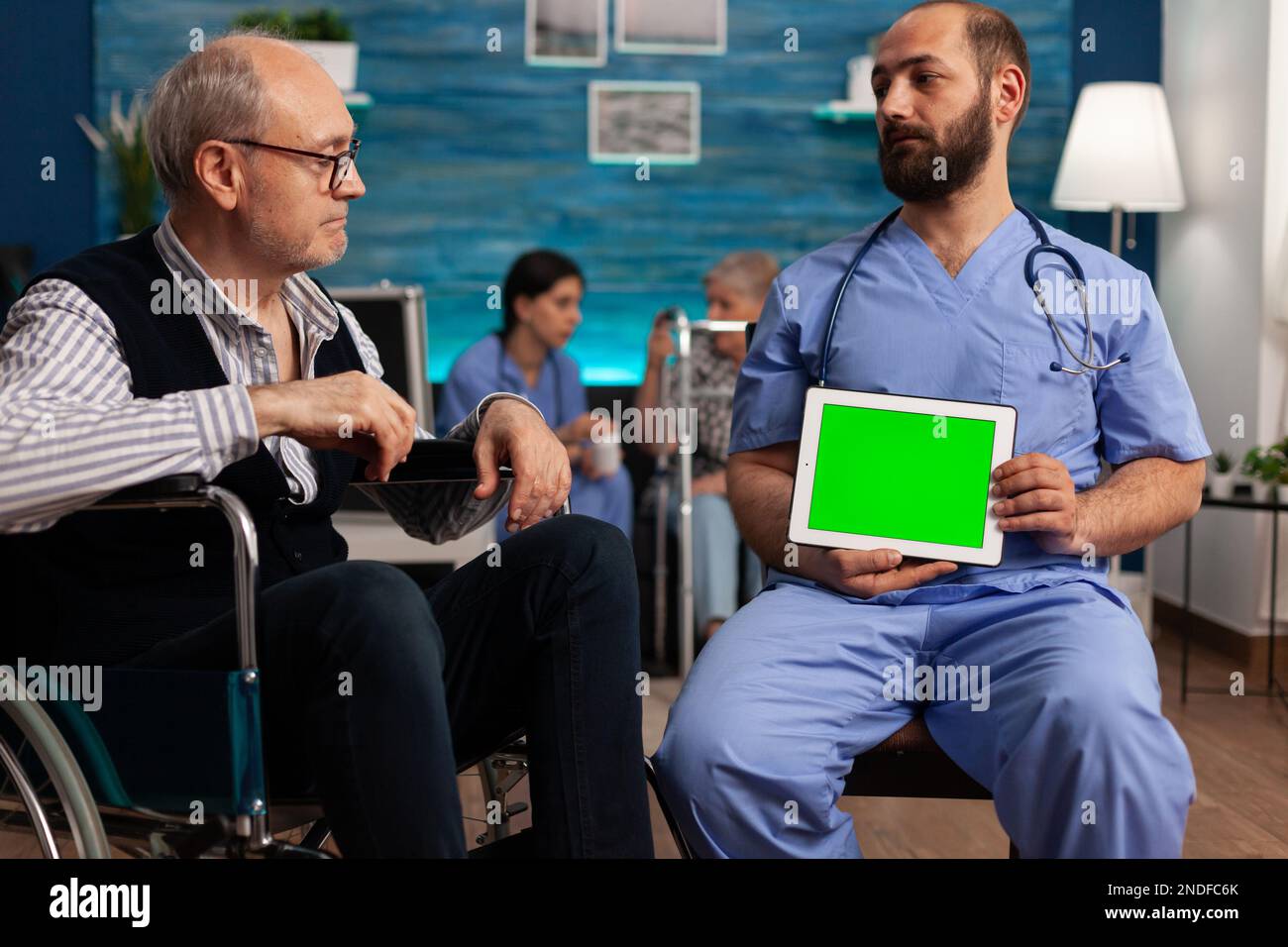 Medical nurse holding a green screen tablet with during a medical ...