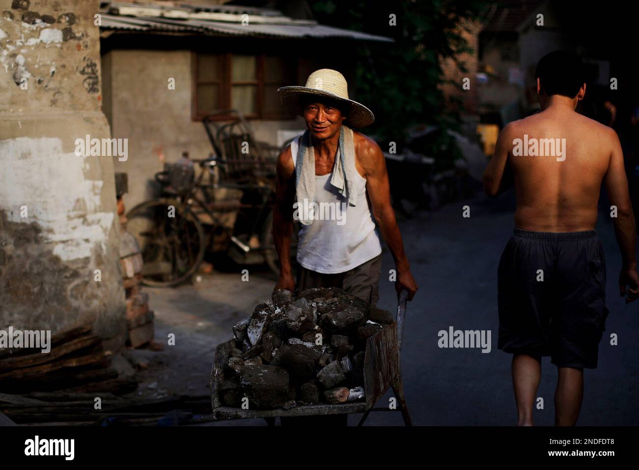 A Chinese man pushes a cart loaded with rocks while working in Hutong ...