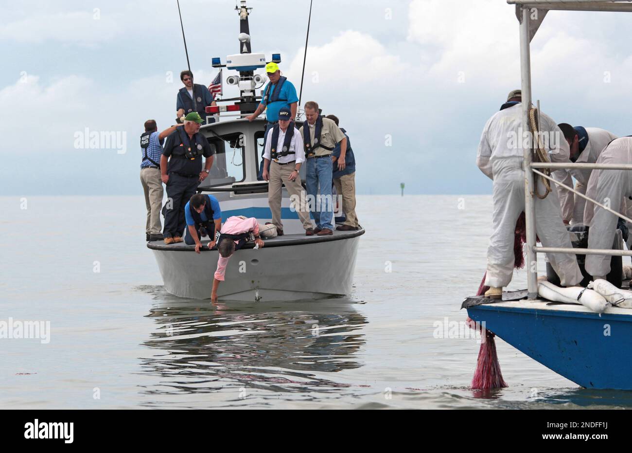 Alabama Gov. Bob Riley reaches into the water to pick up a handful of ...