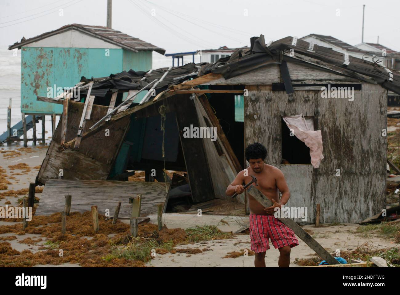 A man works in front of a damaged house after Hurricane Alex hit the ...