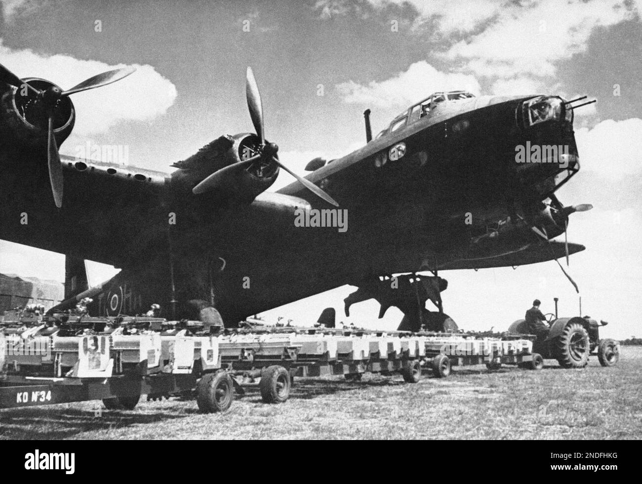 A tractor hauls a load of fire bombs into position to be loaded aboard ...