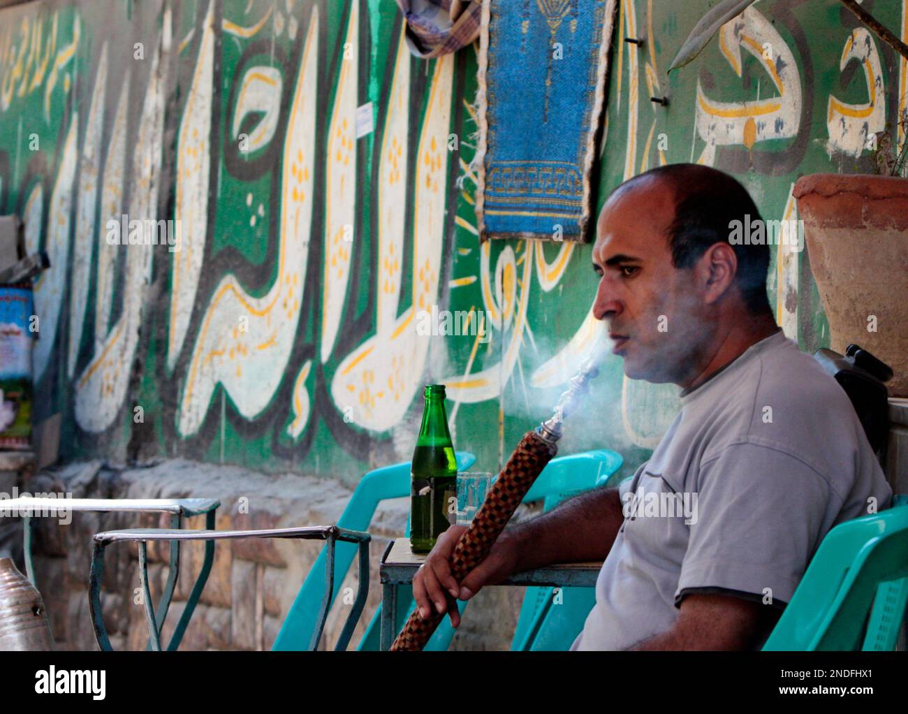 An Egyptian smokes traditional water pipe " Shisha" at a coffee shop in ...