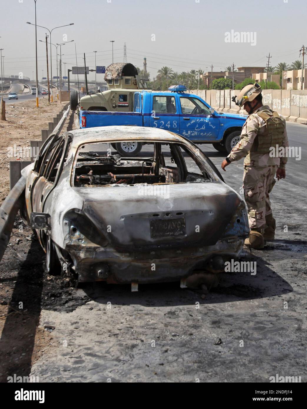 An Iraqi Army solder inspects a destroyed vehicle after a bomb hidden ...