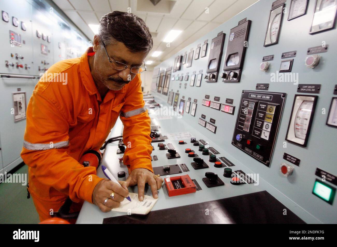 Chief Engineer Ashish Ghosh jots a note in the engine control room on ...