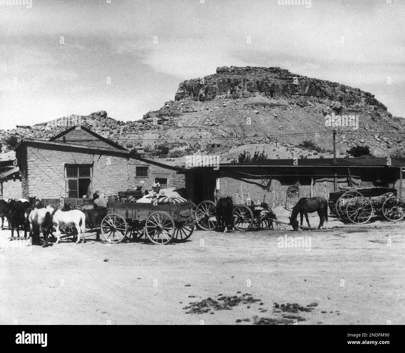 Indians wagons and horses are parked outside the adobe trading post at ...