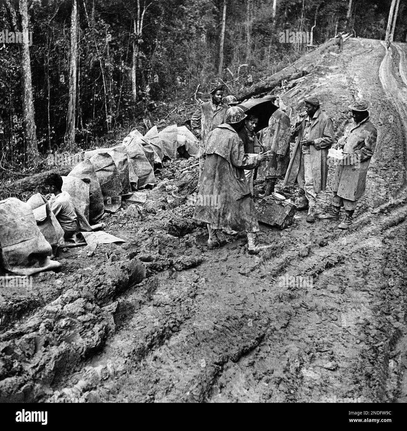 Rain on road during mess time. Native laborers are under raincapes at ...