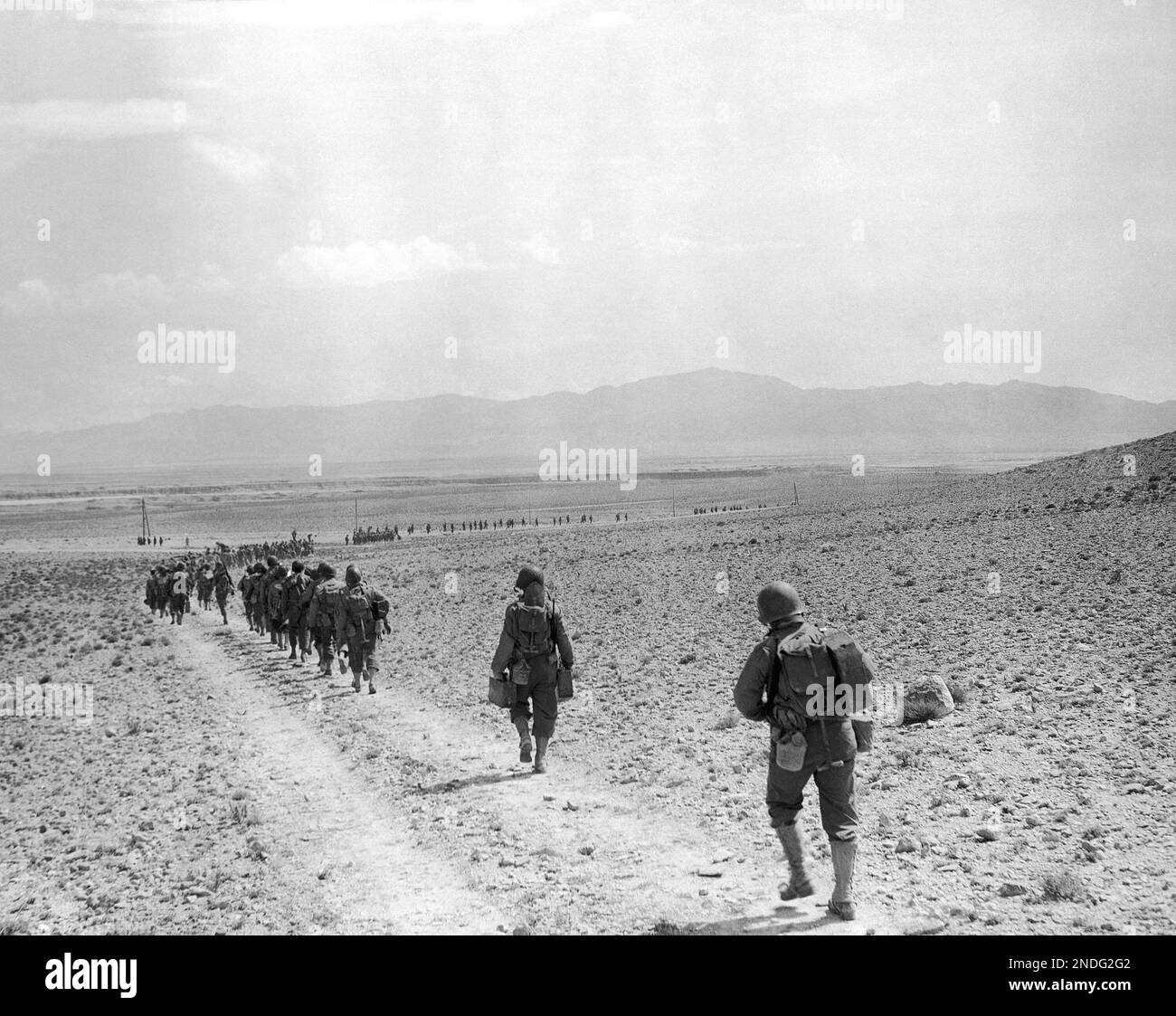 U.S. Army infantrymen march in a long line along the desert road that ...