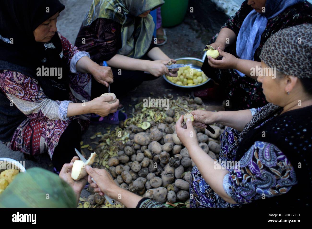 Uzbek women prepare food in the yard of a school building as they seek ...
