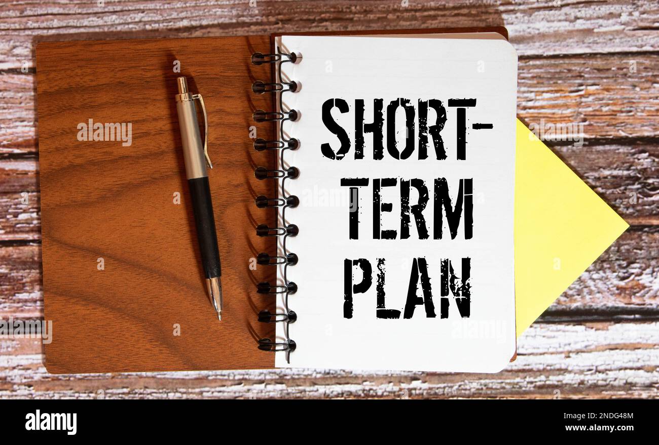 Notebook with text SHORT-TERM PLAN on a table with charts,pen and ...