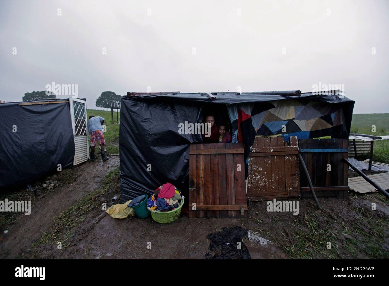 People look from their shack entrance after their home was destroyed by ...