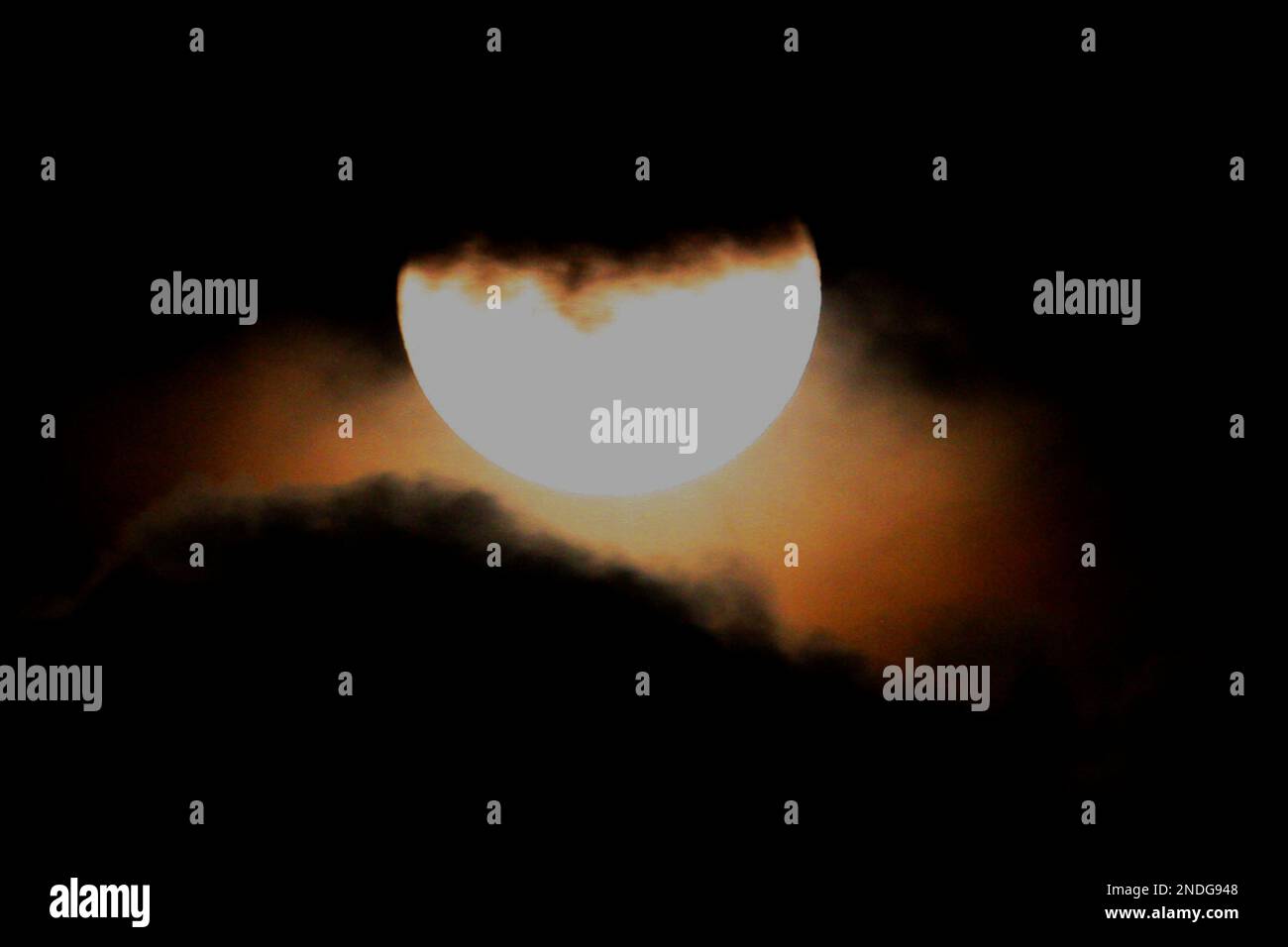 The moon can be seen behind clouds in Nairobi, Kenya, after a partial ...