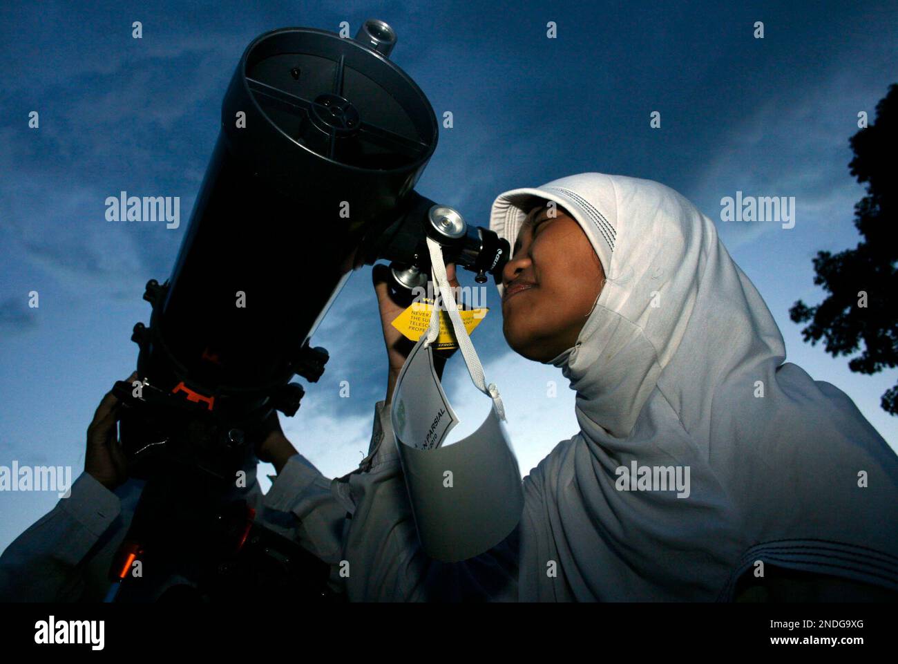 Indonesian student uses binoculars to look at a lunar eclipse in Yogyakarta, Central Java ...