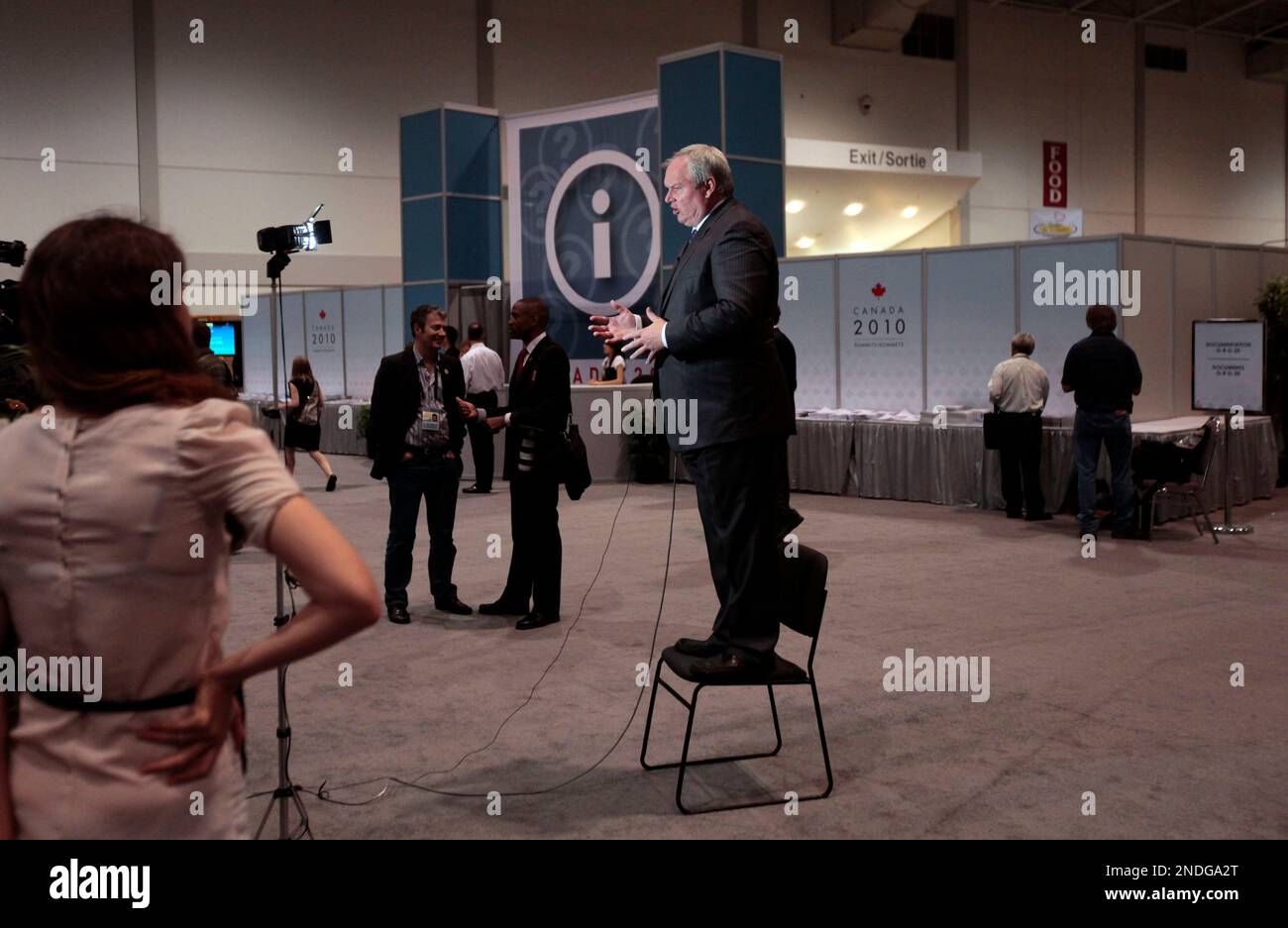 A British TV journalist stands on a chair to give a live report from ...