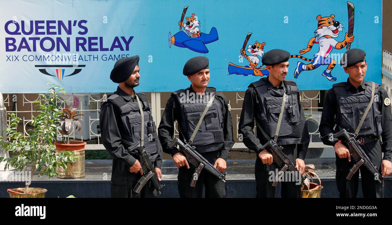 Indian security personnel stand in front of a sign showing the Queen's ...